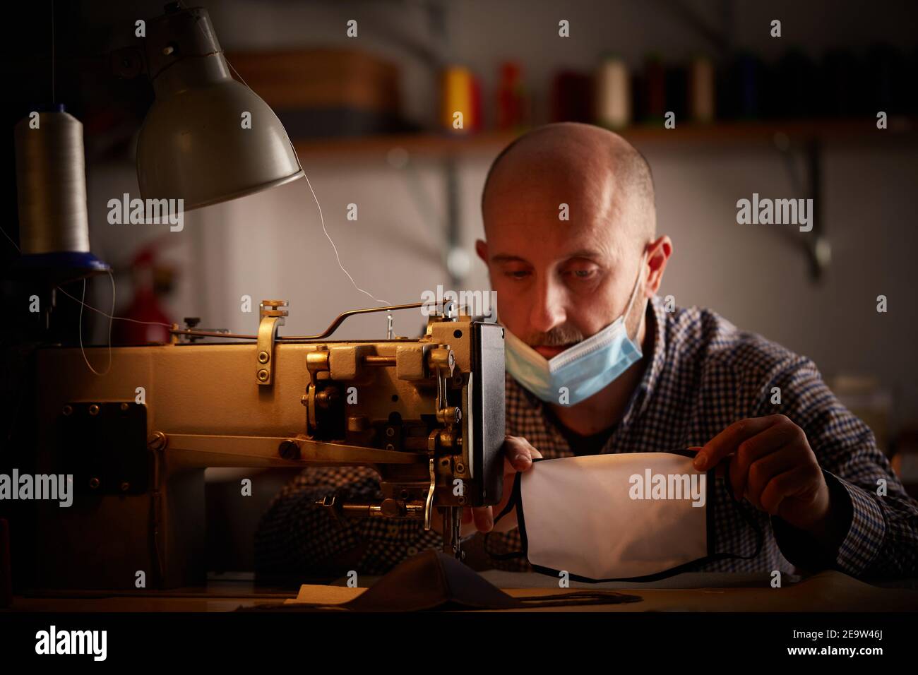 man working with sewing machine doing homemade face mask for preventing ...