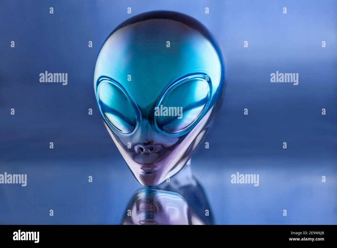 alien metal head statue on blue background on the table Stock Photo - Alamy