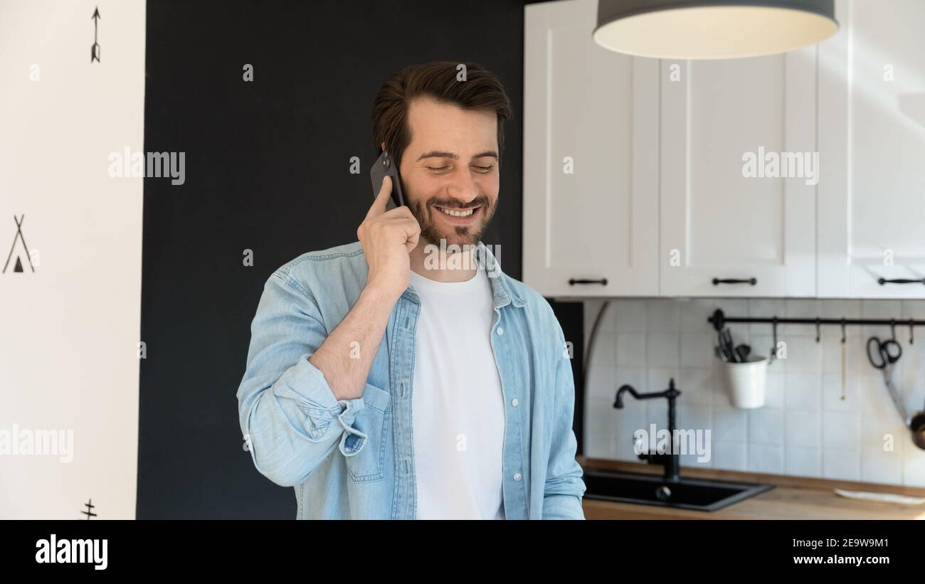 Happy millennial male involved in pleasant phone conversation at ...