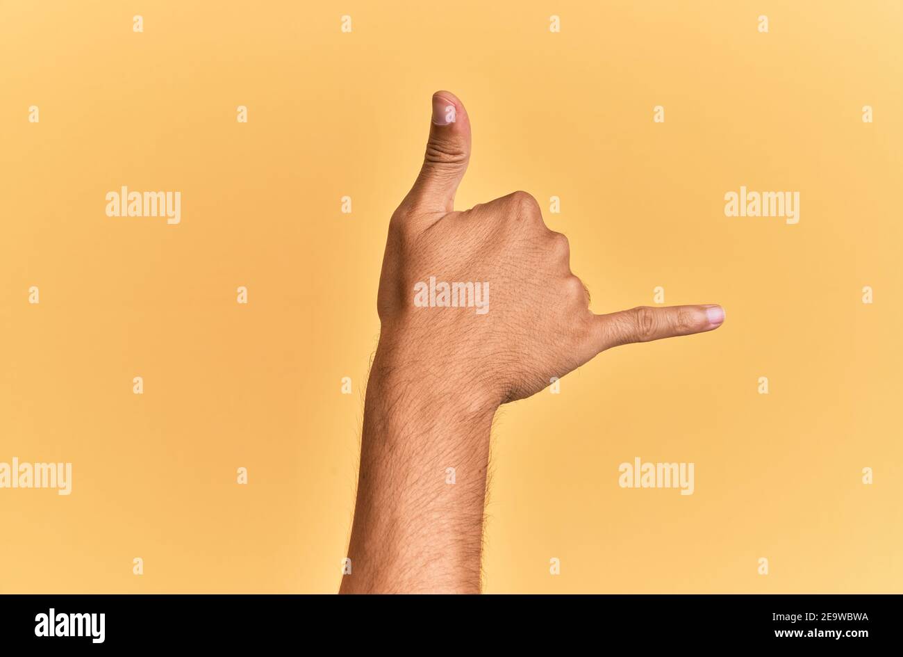 Arm and hand of caucasian man over yellow isolated background gesturing ...