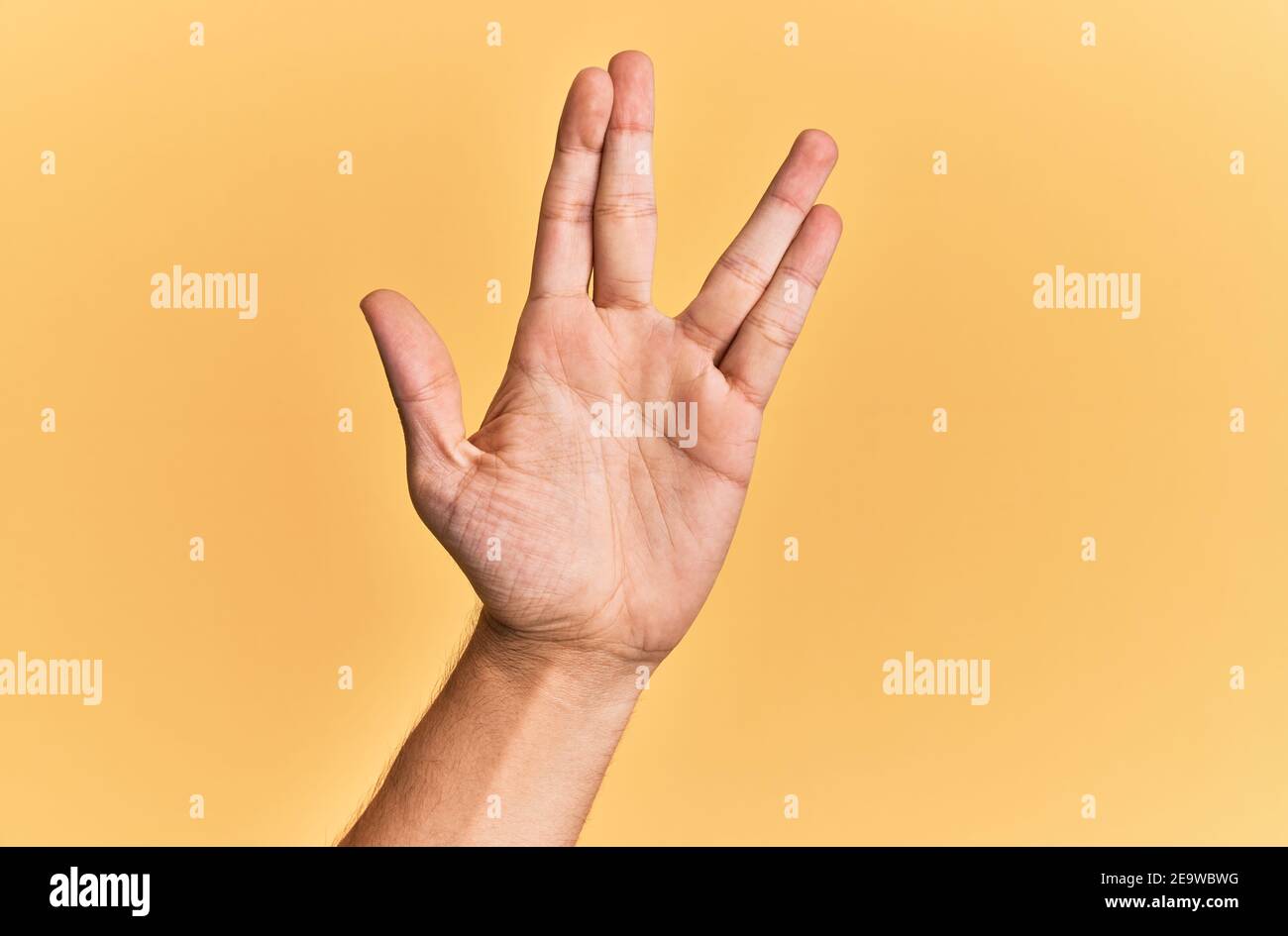 Arm and hand of caucasian man over yellow isolated background greeting ...