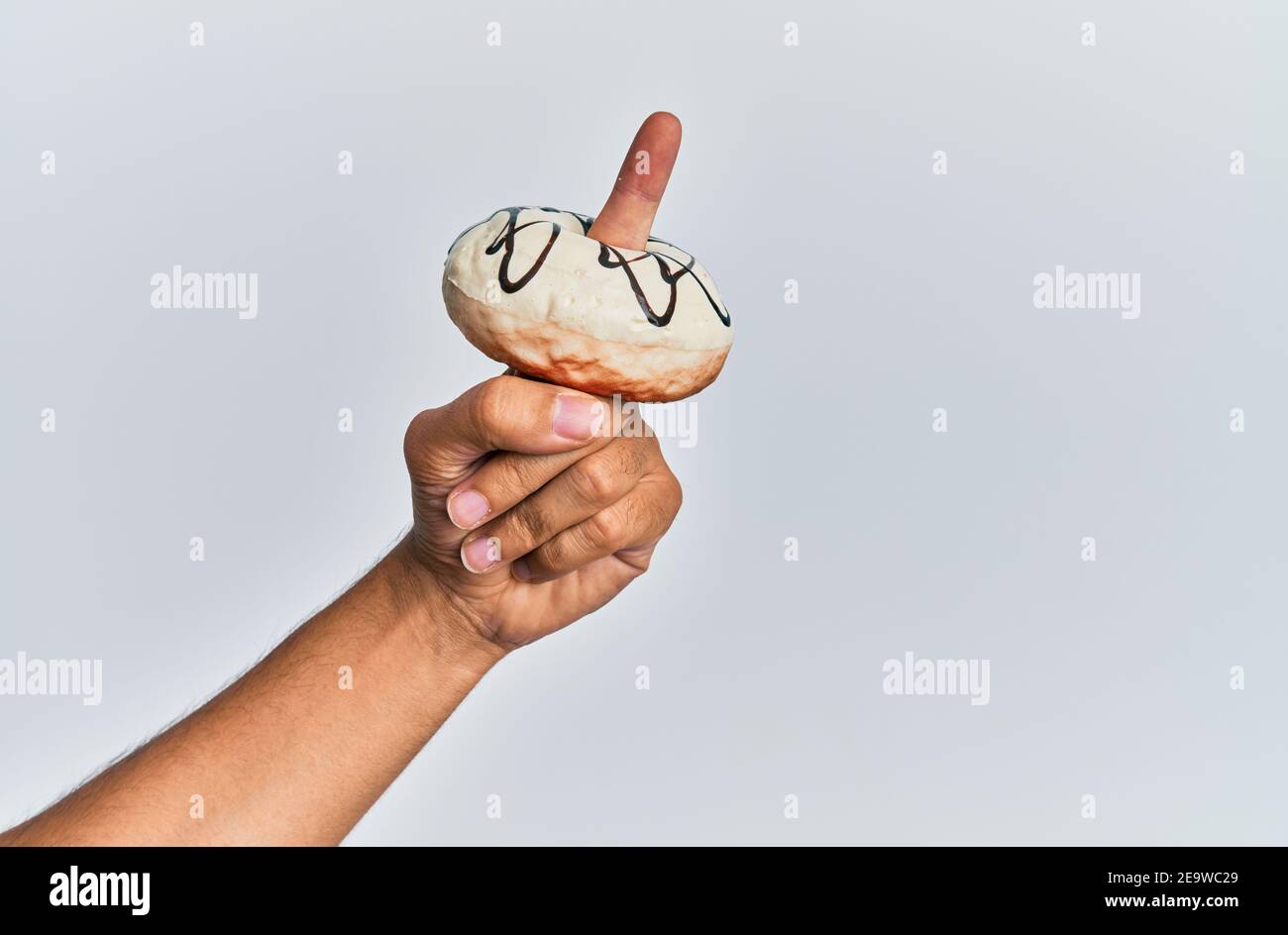 Finger of hispanic man holding donut over isolated white background ...