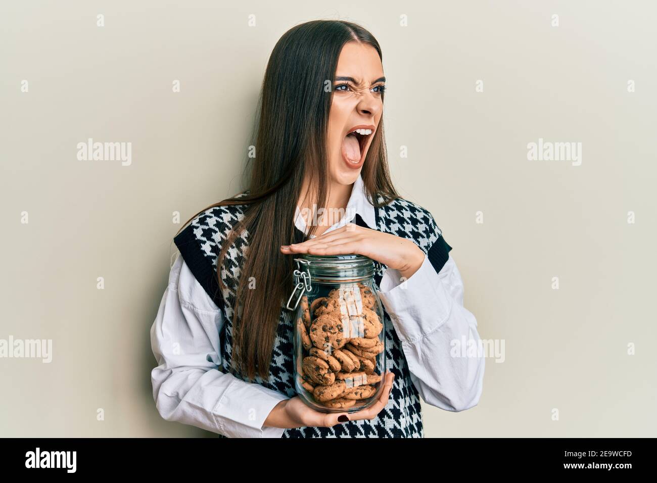 Beautiful brunette young woman holding jar of chocolate chips cookies ...