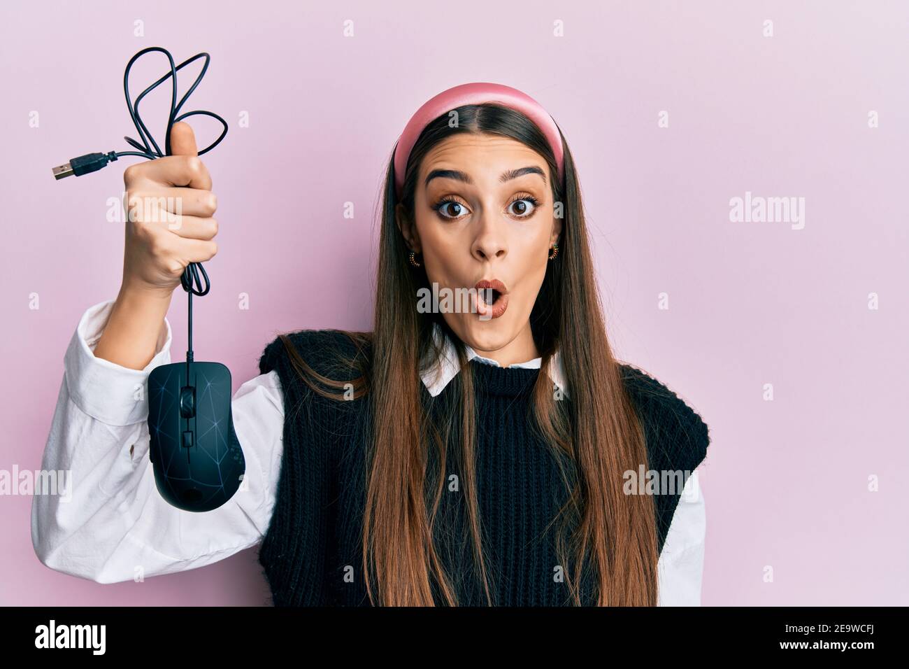 Beautiful brunette young woman holding computer mouse device scared and ...