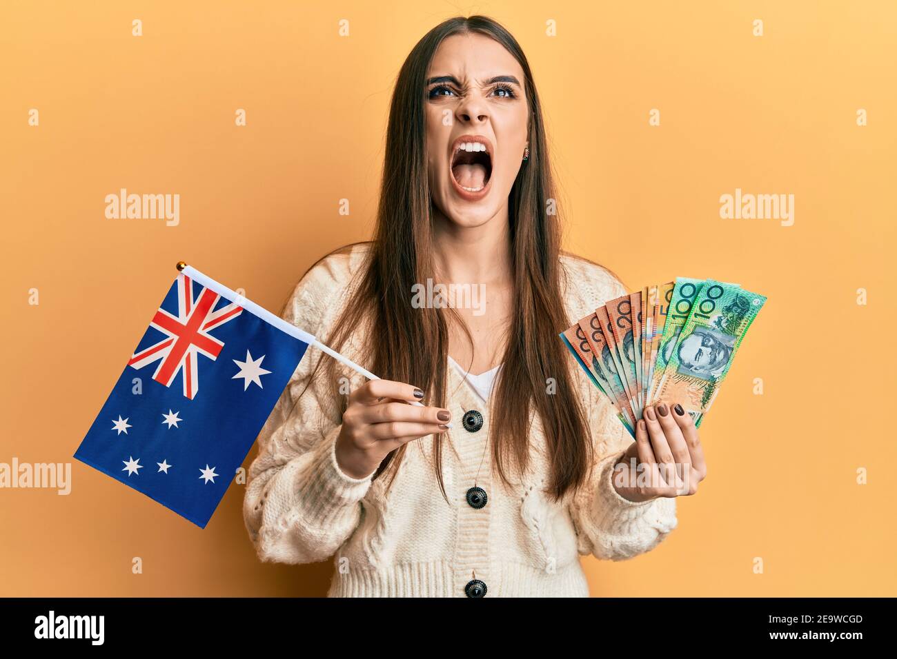 Beautiful brunette young woman holding australian flag and dollars ...