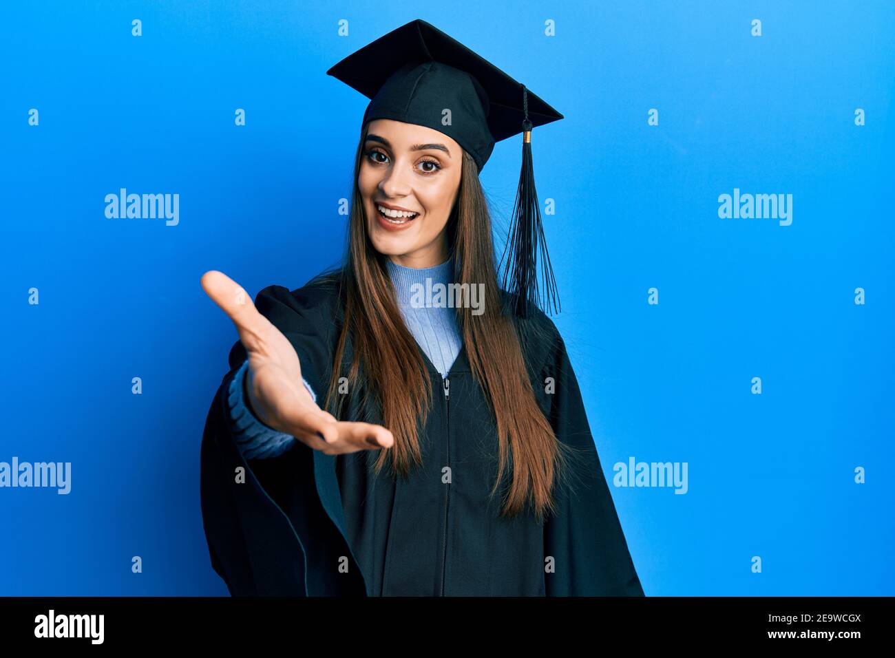 Beautiful brunette young woman wearing graduation cap and ceremony robe ...