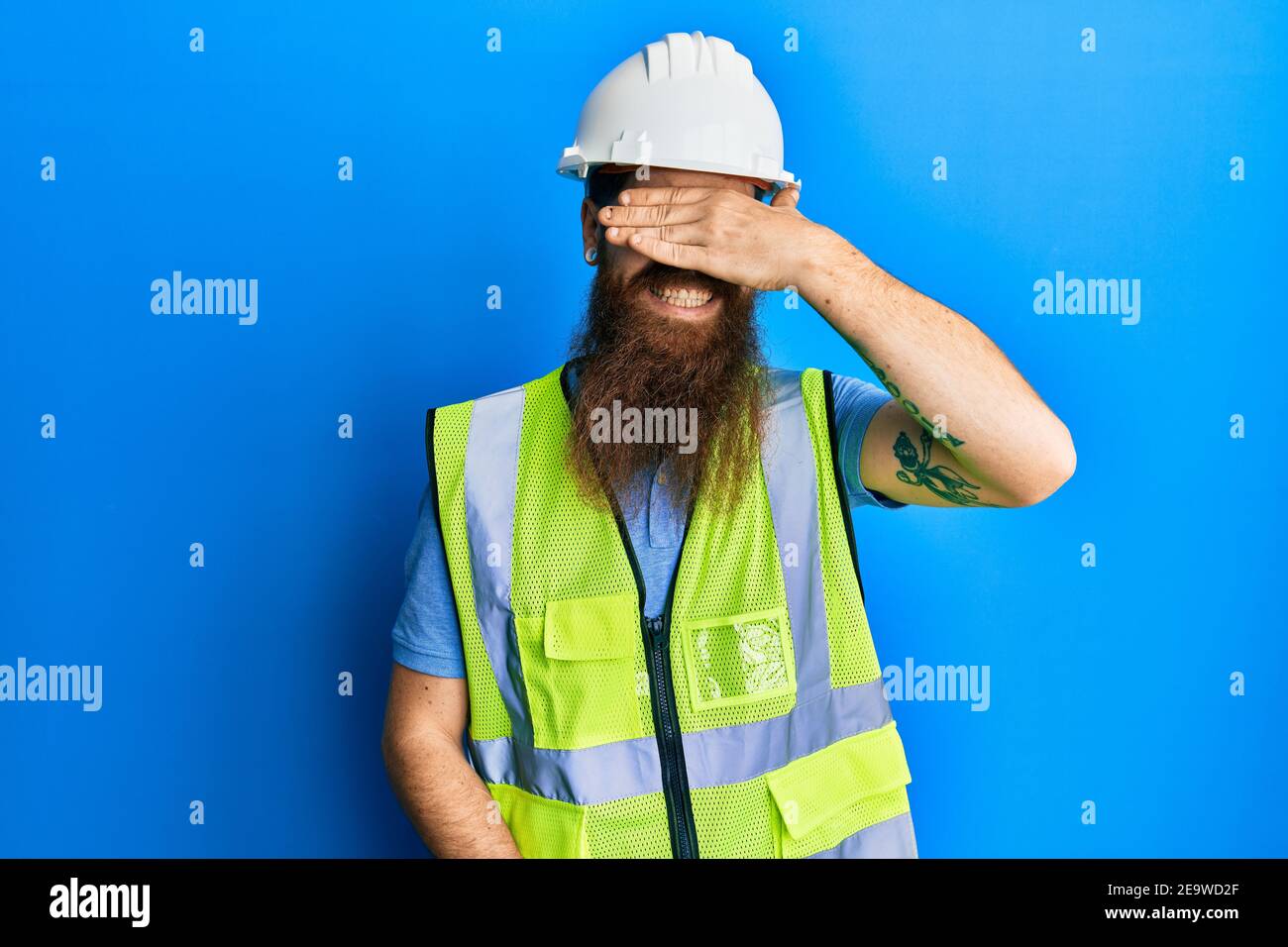 Redhead man with long beard wearing safety helmet and reflective jacket ...