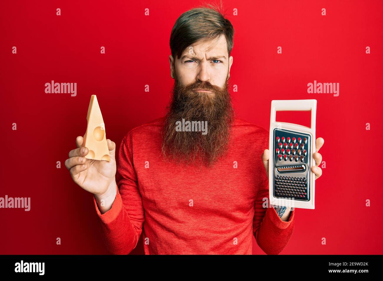 Redhead man with long beard holding grater and cheese depressed and ...