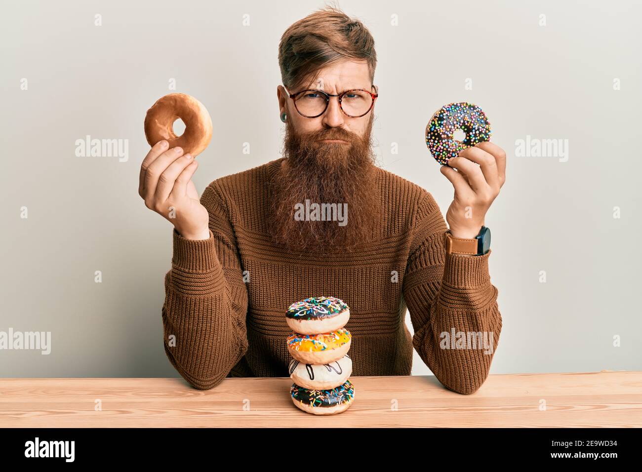 Young irish redhead man eating doughnut for breakfast depressed and ...