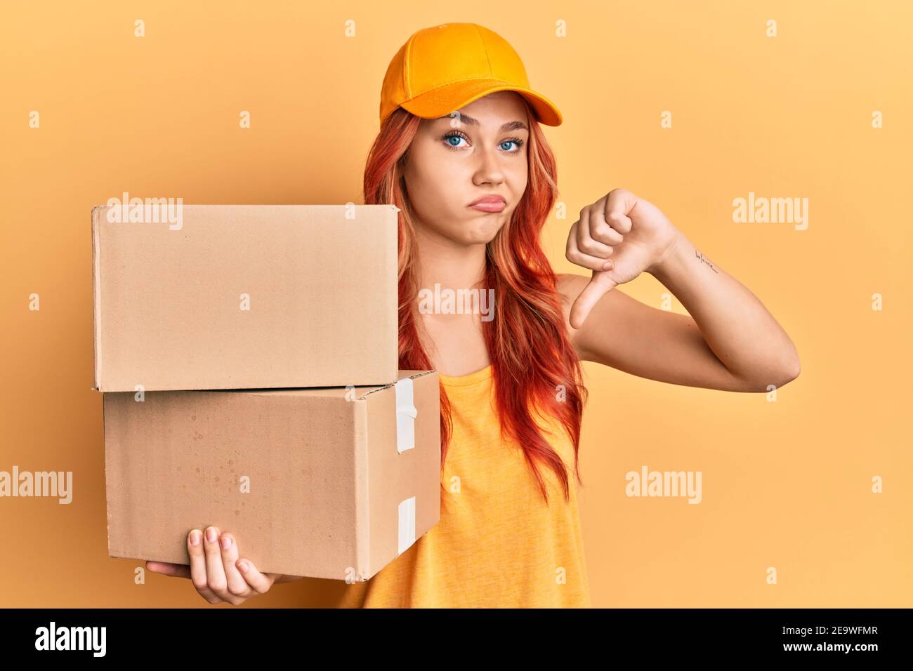 Young redhead woman holding delivery package with angry face, negative ...
