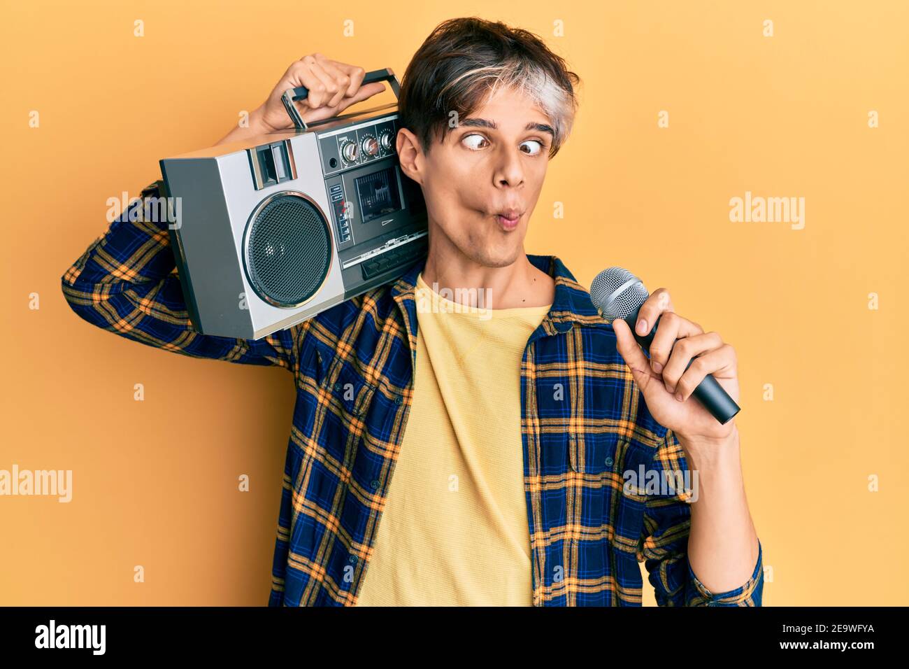 Young hispanic man singing song using microphone and boombox making ...