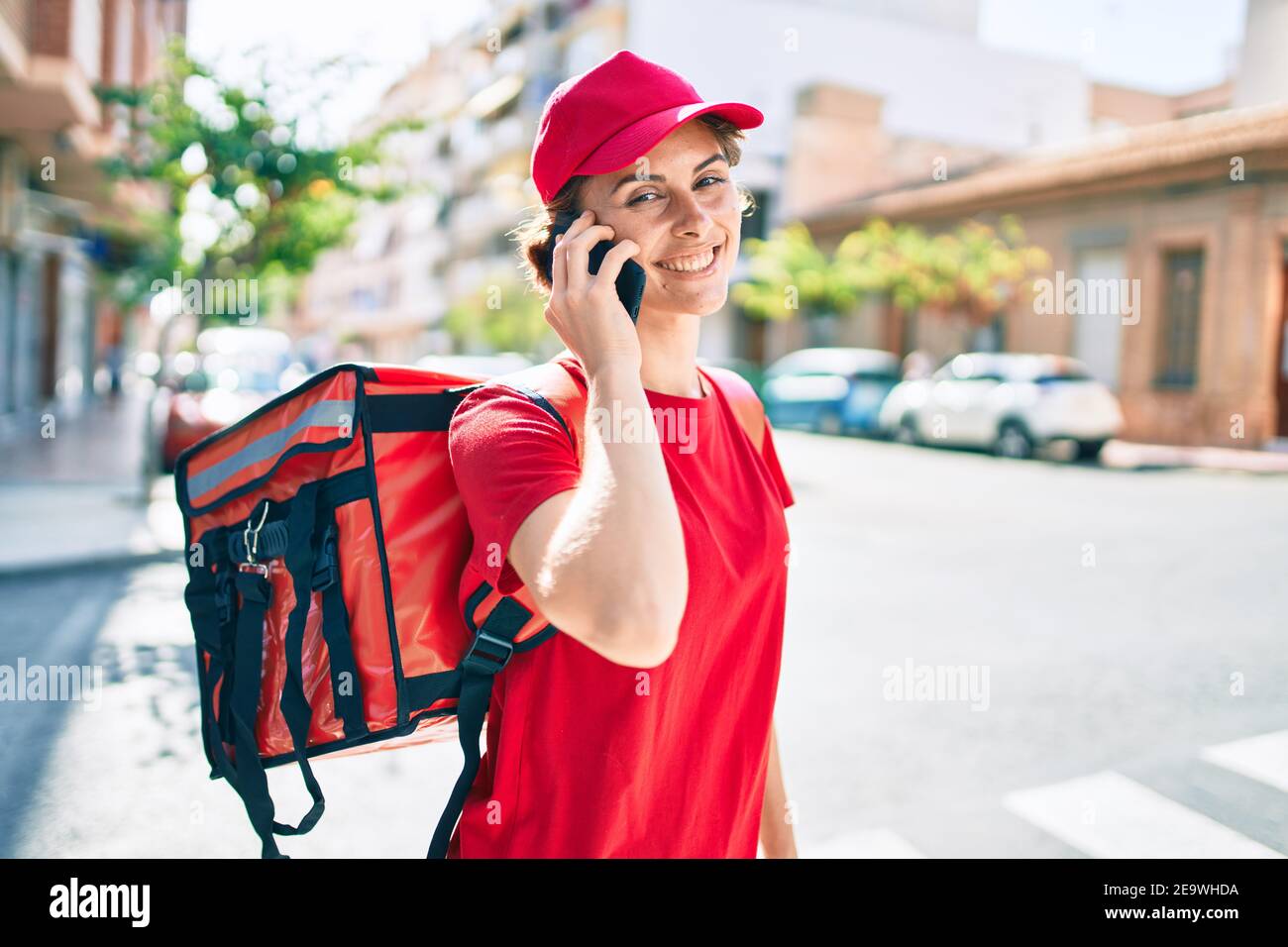 Delivery business worker woman wearing uniform and delivery bag smiling happy speaking on the ...