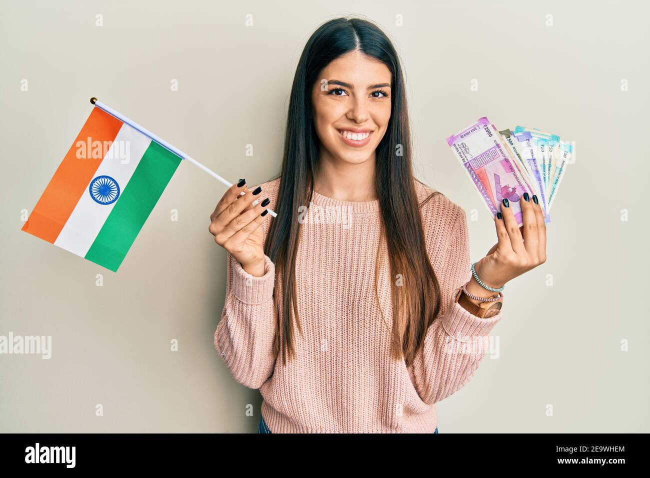 Young hispanic woman holding india flag and rupee banknotes smiling ...