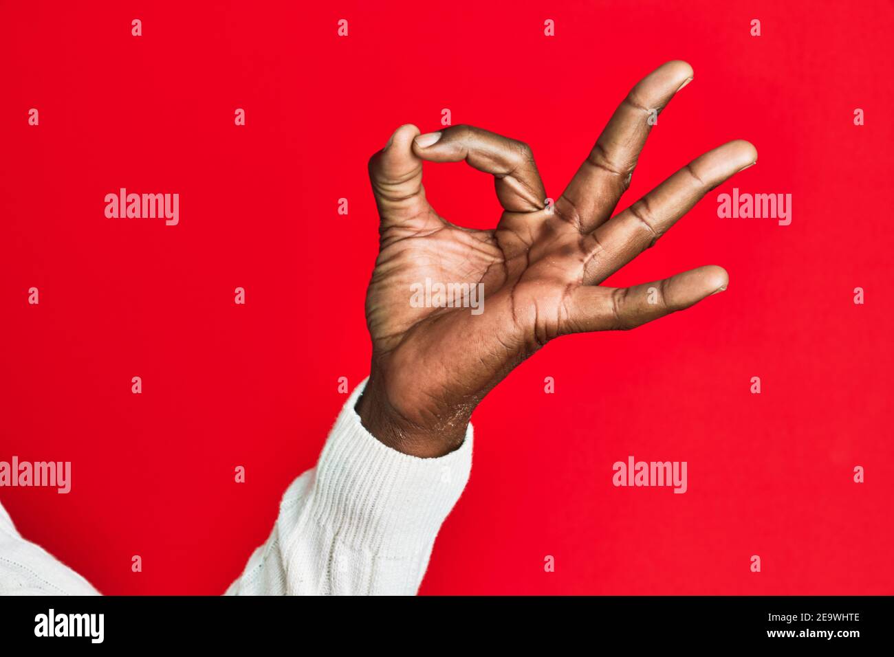 Arm and hand of african american black young man over red isolated ...