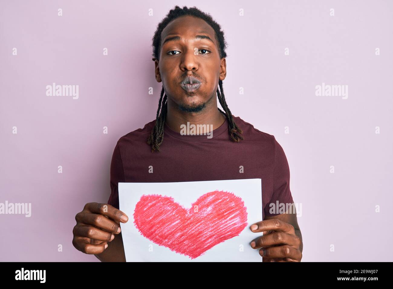 African american man with braids holding heart draw puffing cheeks with ...