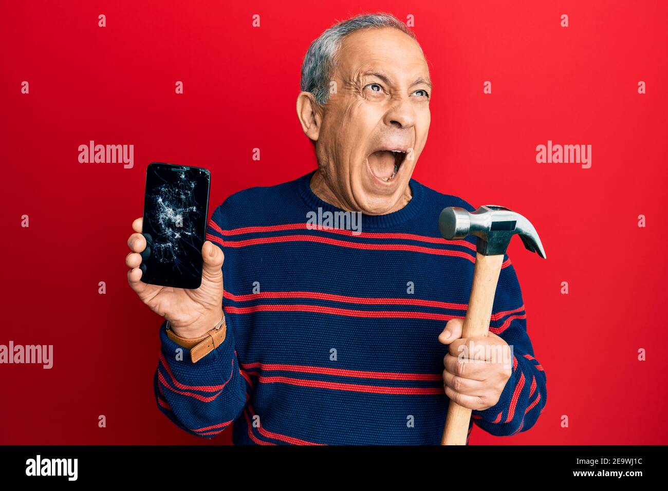 Senior hispanic man holding broken smartphone showing cracked screen ...