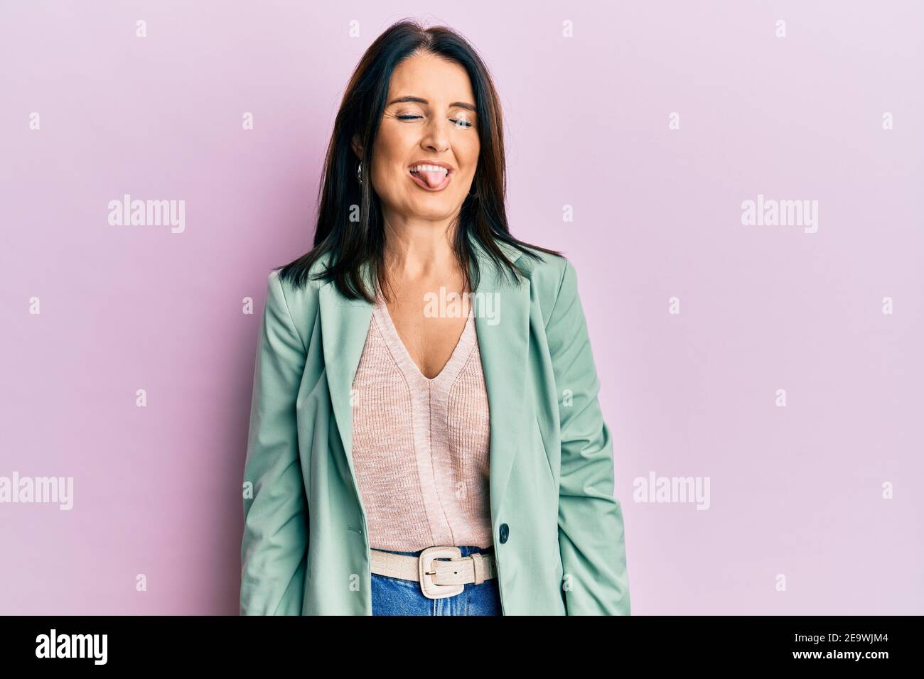 Middle age brunette woman wearing casual clothes sticking tongue out ...