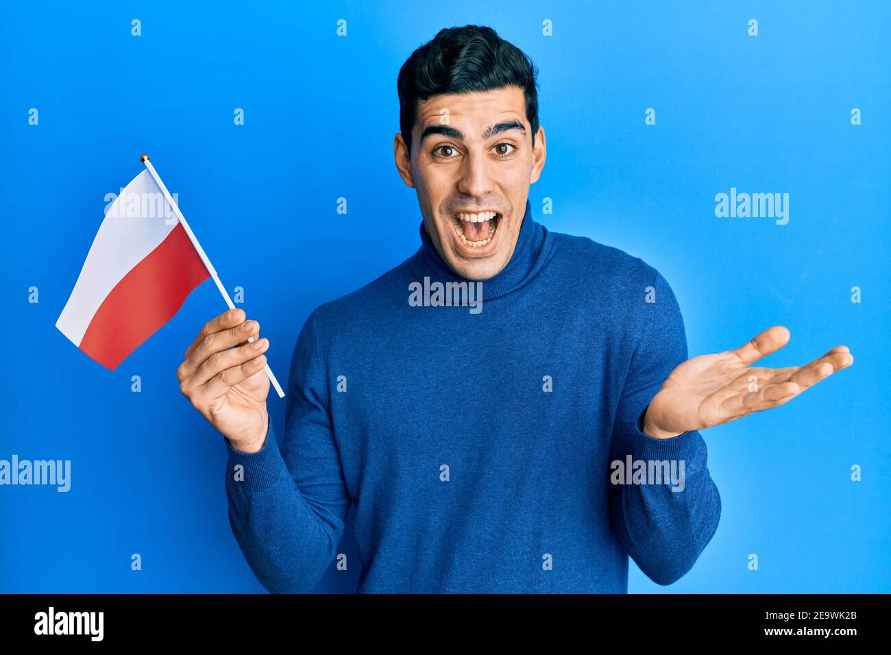 Handsome hispanic man holding poland flag celebrating achievement with ...