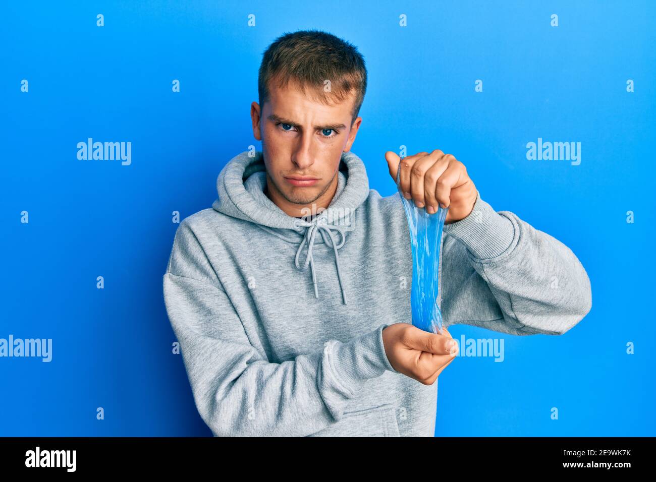 Young caucasian man holding slime depressed and worry for distress ...