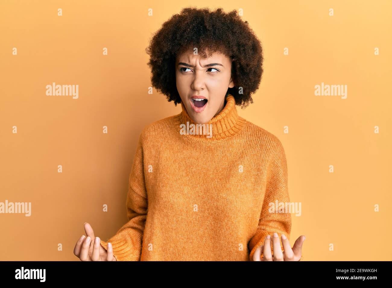 Young hispanic girl wearing wool winter sweater crazy and mad shouting ...