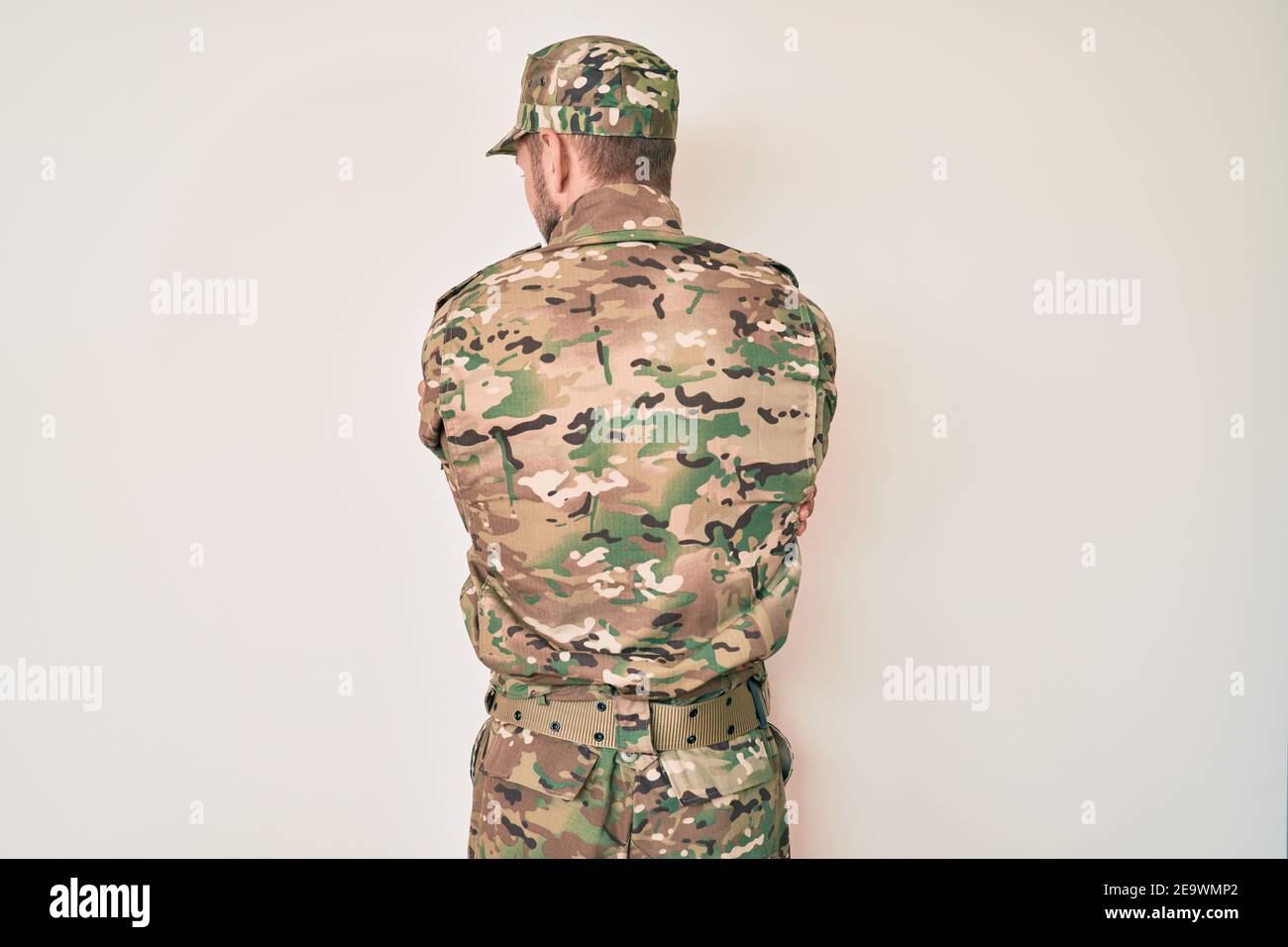 Young caucasian man wearing camouflage army uniform hugging oneself ...