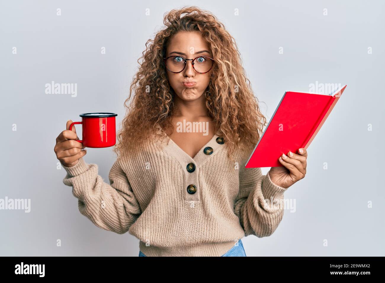 Beautiful caucasian teenager girl reading a book and drinking a cup of ...