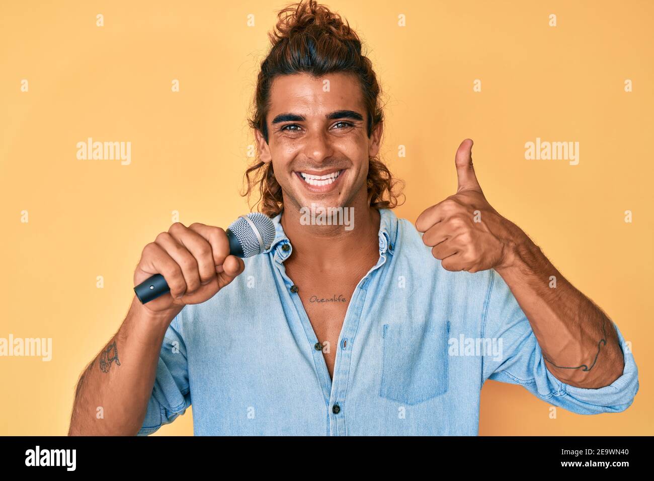 Young hispanic man singing song using microphone smiling happy and ...