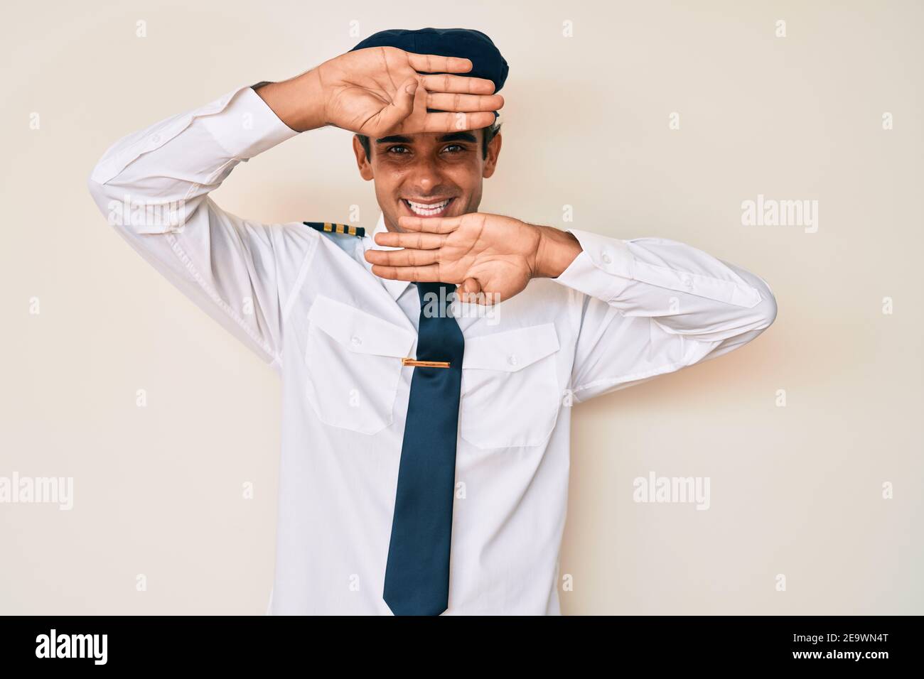Young hispanic man wearing airplane pilot uniform smiling cheerful ...