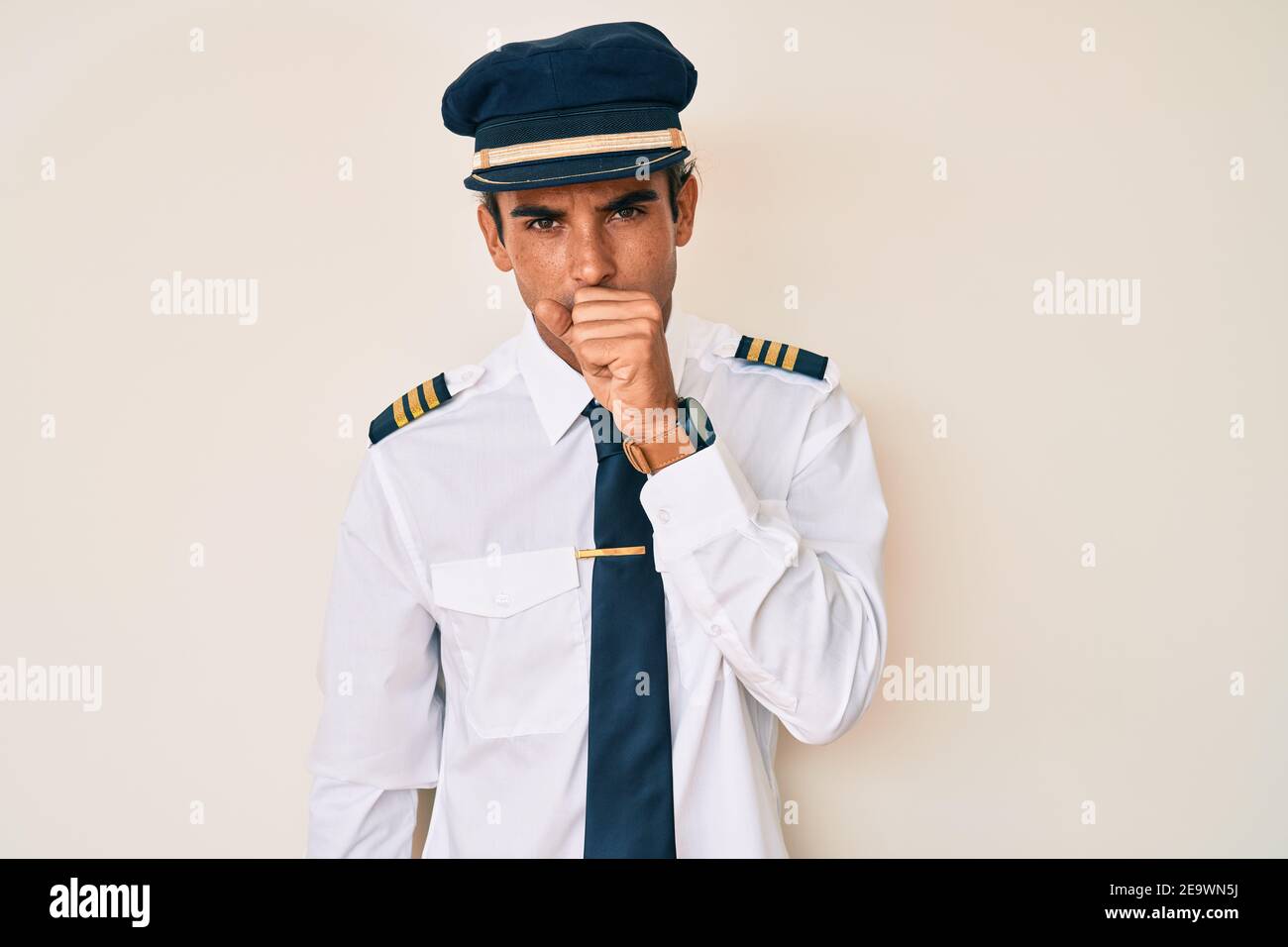 Young hispanic man wearing airplane pilot uniform feeling unwell and ...
