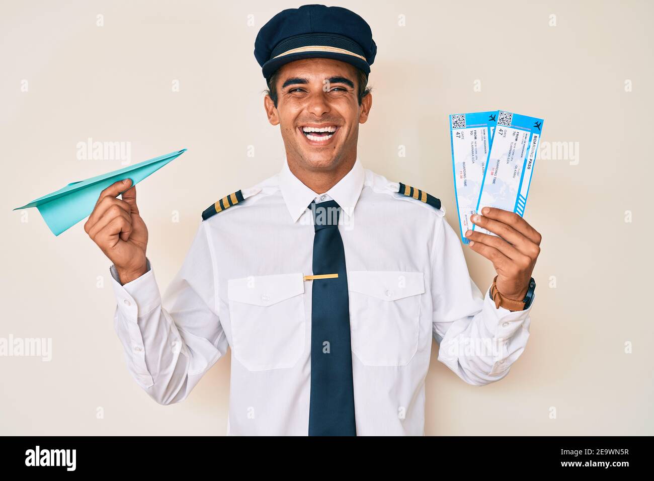 Young hispanic man wearing airplane pilot uniform holding paper ...