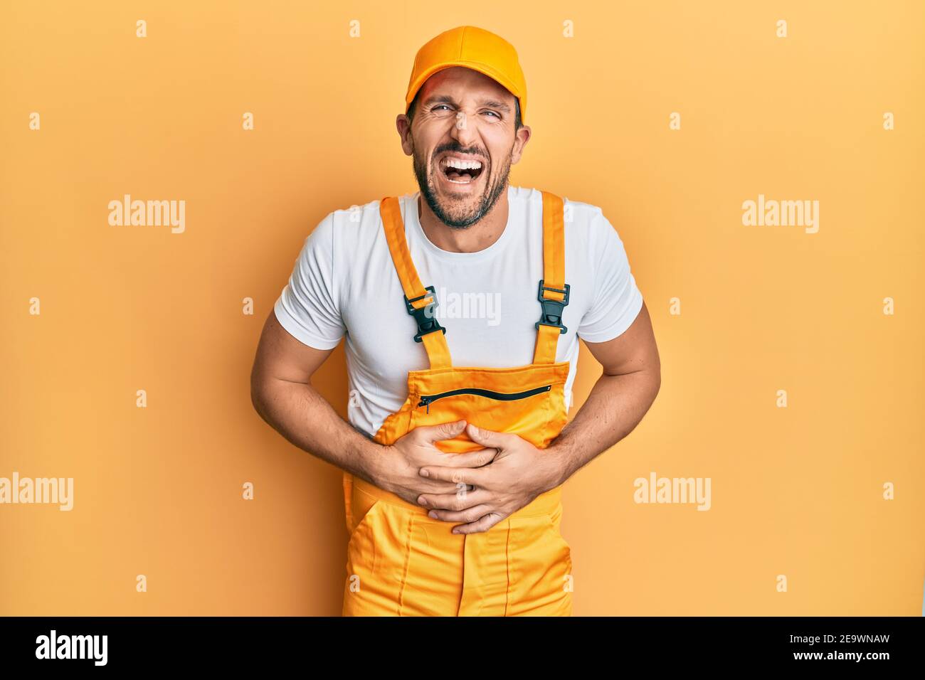 Young handsome man wearing handyman uniform over yellow background ...