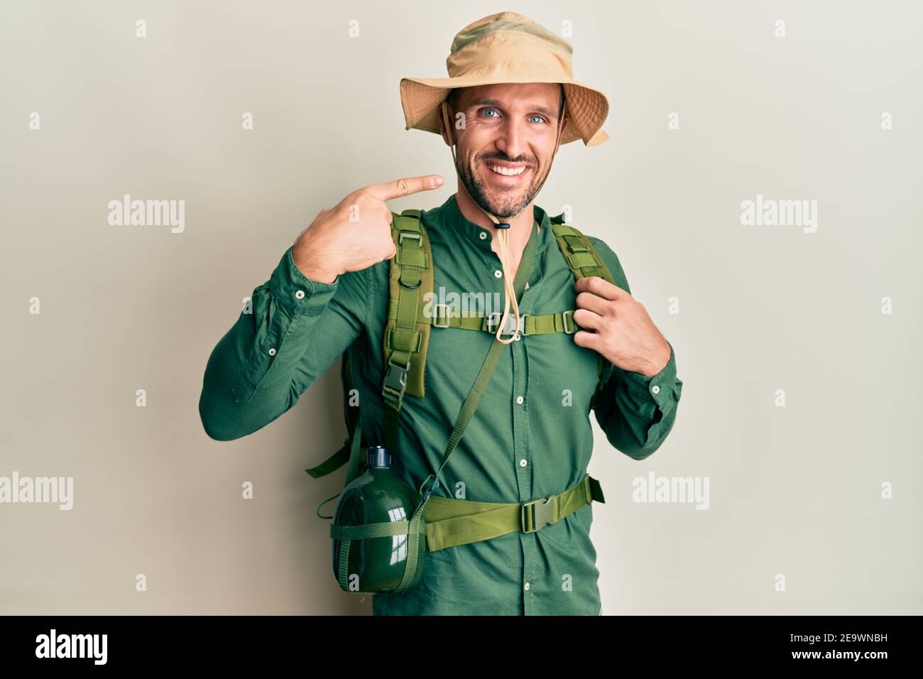 Handsome man with beard wearing explorer hat and backpack smiling ...