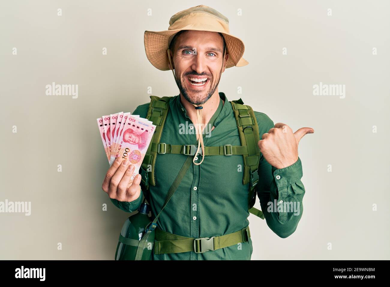Handsome man with beard wearing explorer hat holding 100 yuan banknotes ...