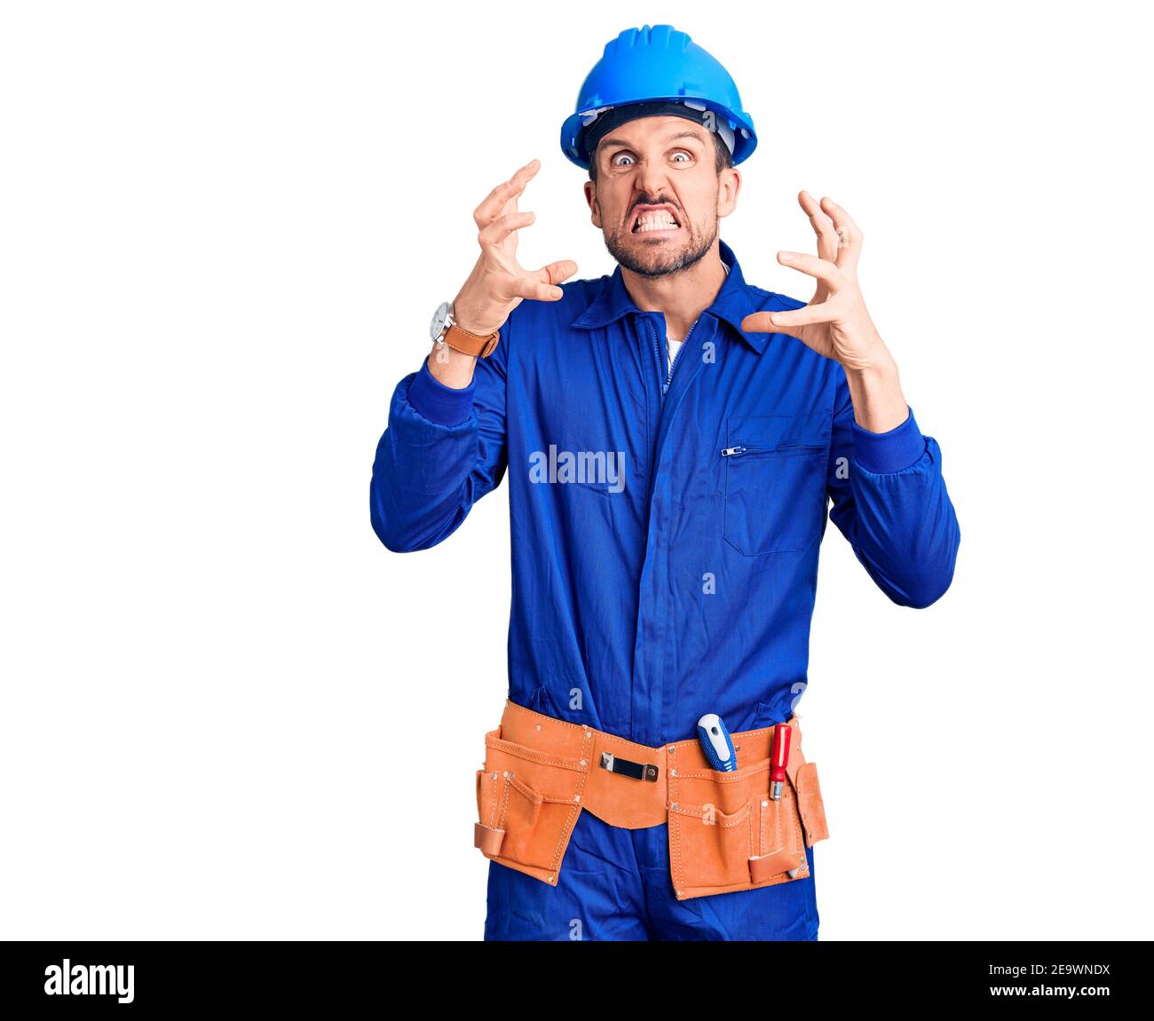 Young handsome man wearing worker uniform and hardhat angry and mad ...