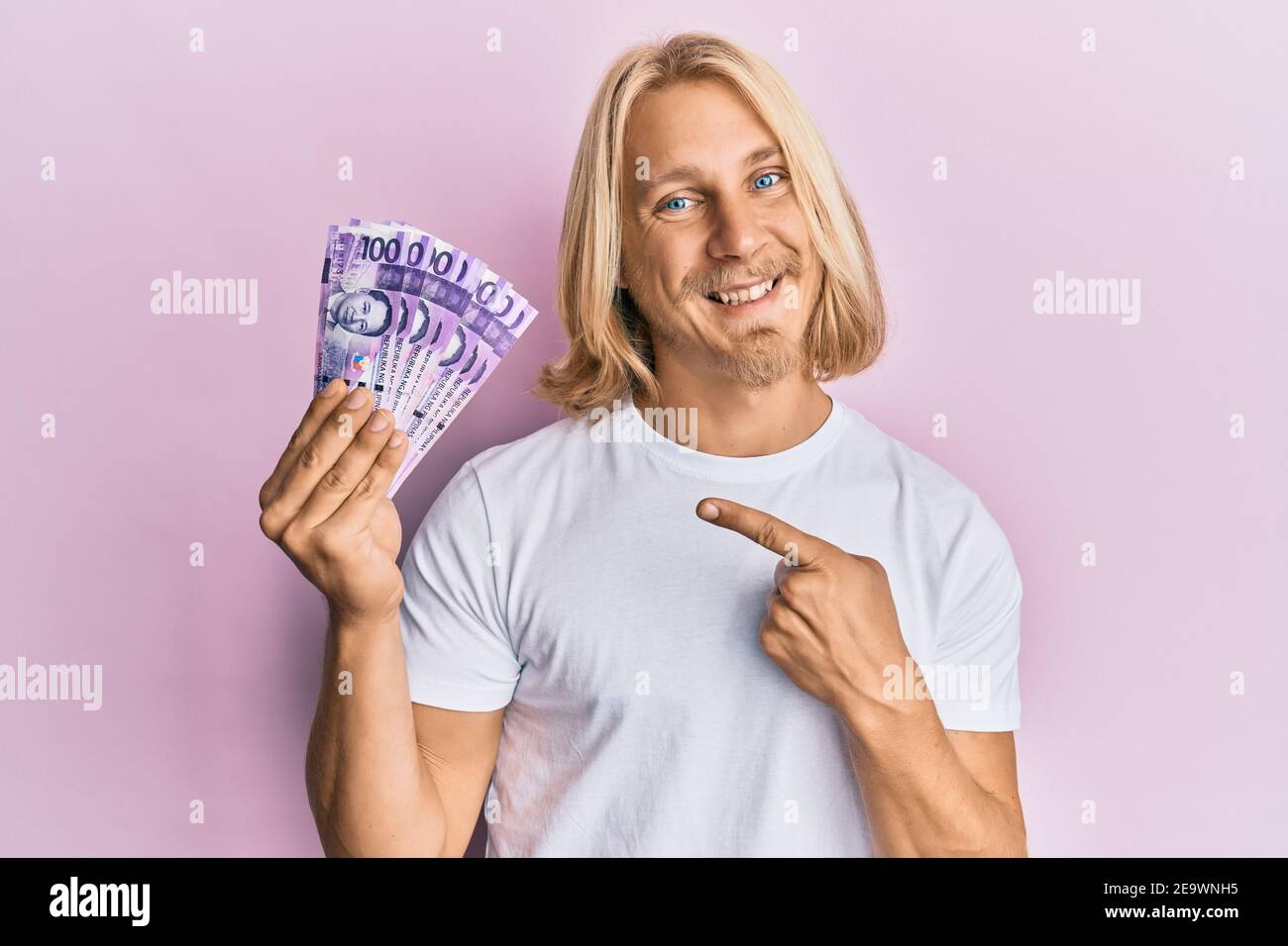 Caucasian young man with long hair holding 100 philippine peso ...