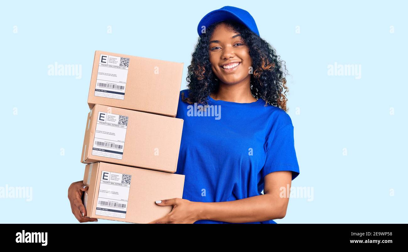 Young african american woman holding delivery package looking positive ...