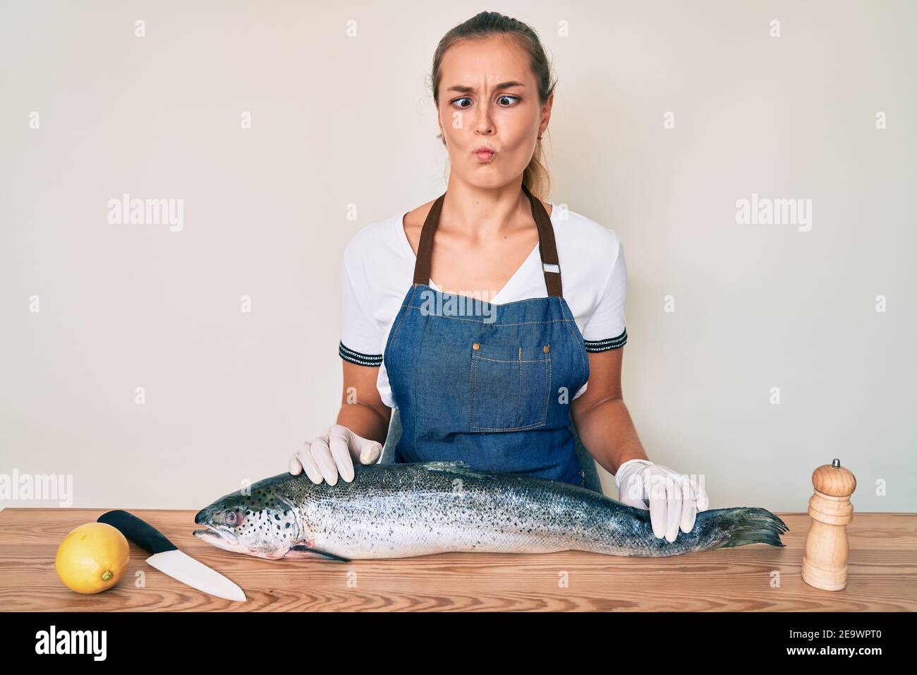 Beautiful caucasian woman fishmonger selling fresh raw salmon making ...