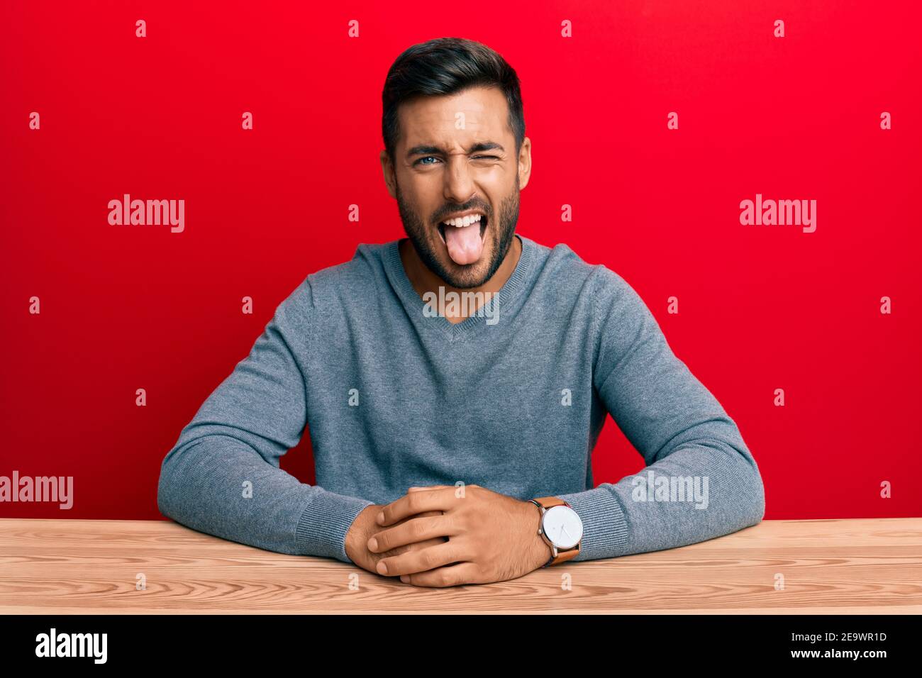 Handsome hispanic man wearing casual style sitting on the table ...