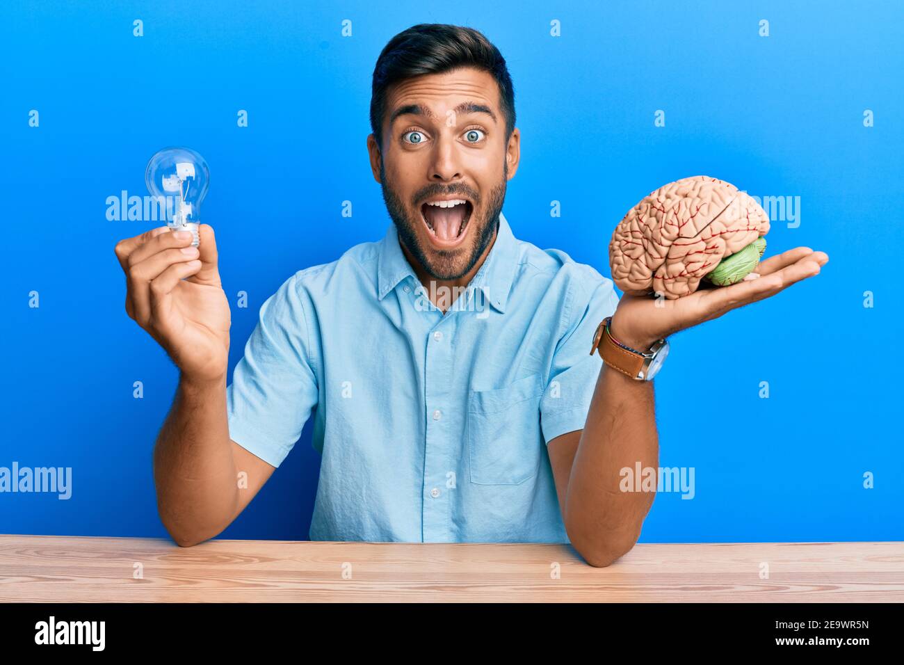 Handsome hispanic man holding lightbulb and brain for inspiration and ...