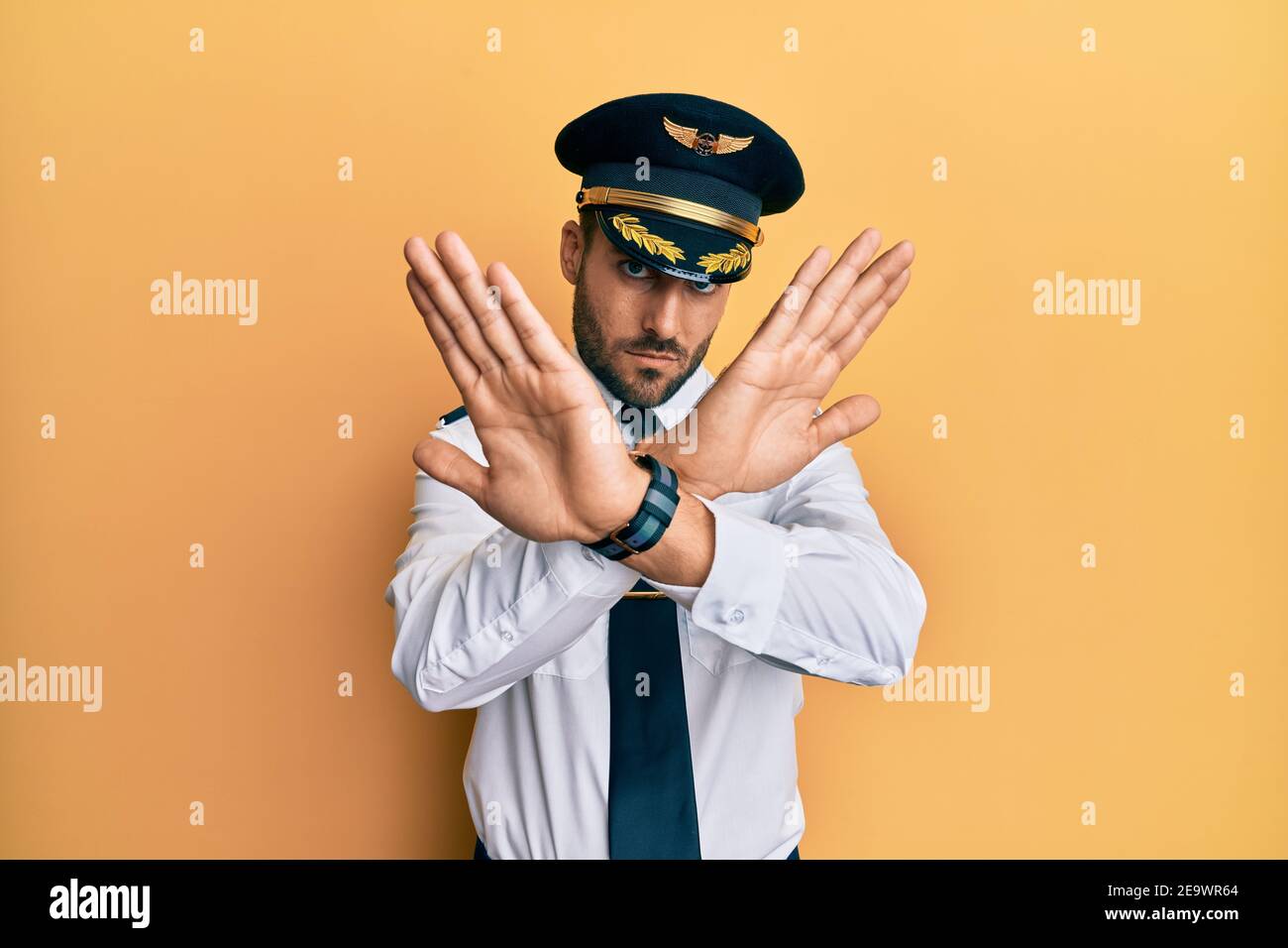 Handsome hispanic man wearing airplane pilot uniform rejection ...