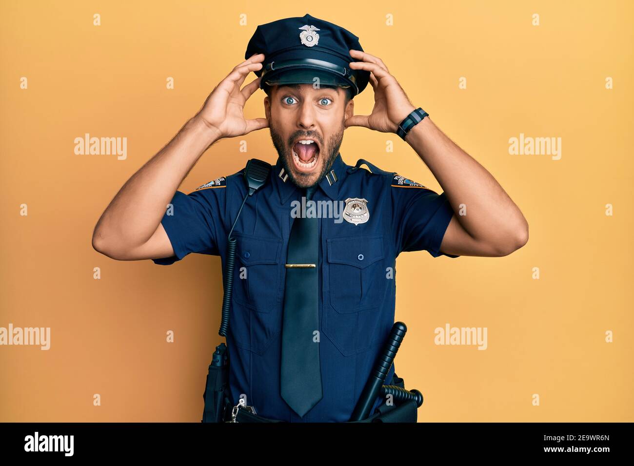 Handsome hispanic man wearing police uniform crazy and scared with ...