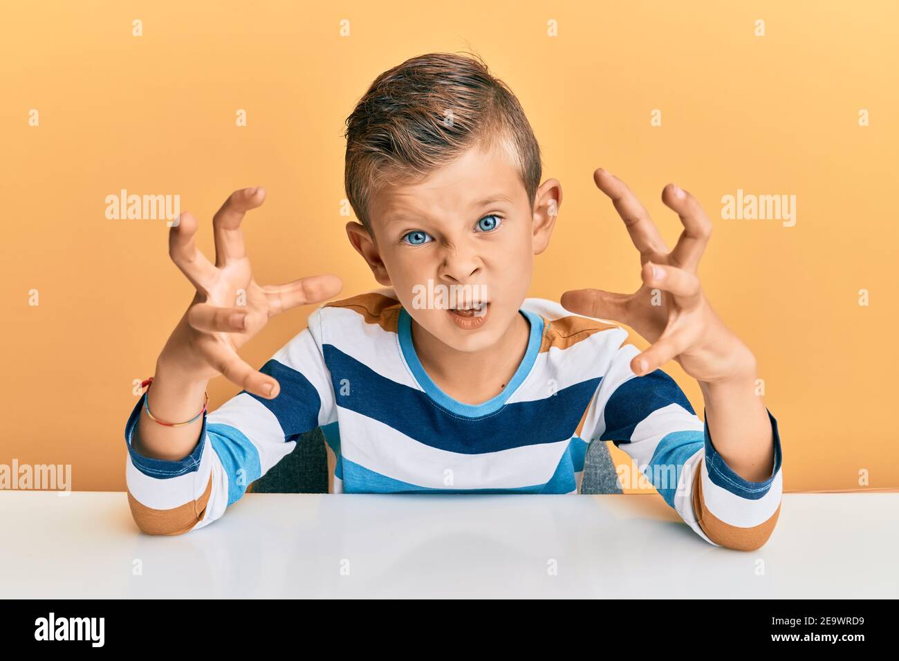 Adorable caucasian kid wearing casual clothes sitting on the table ...