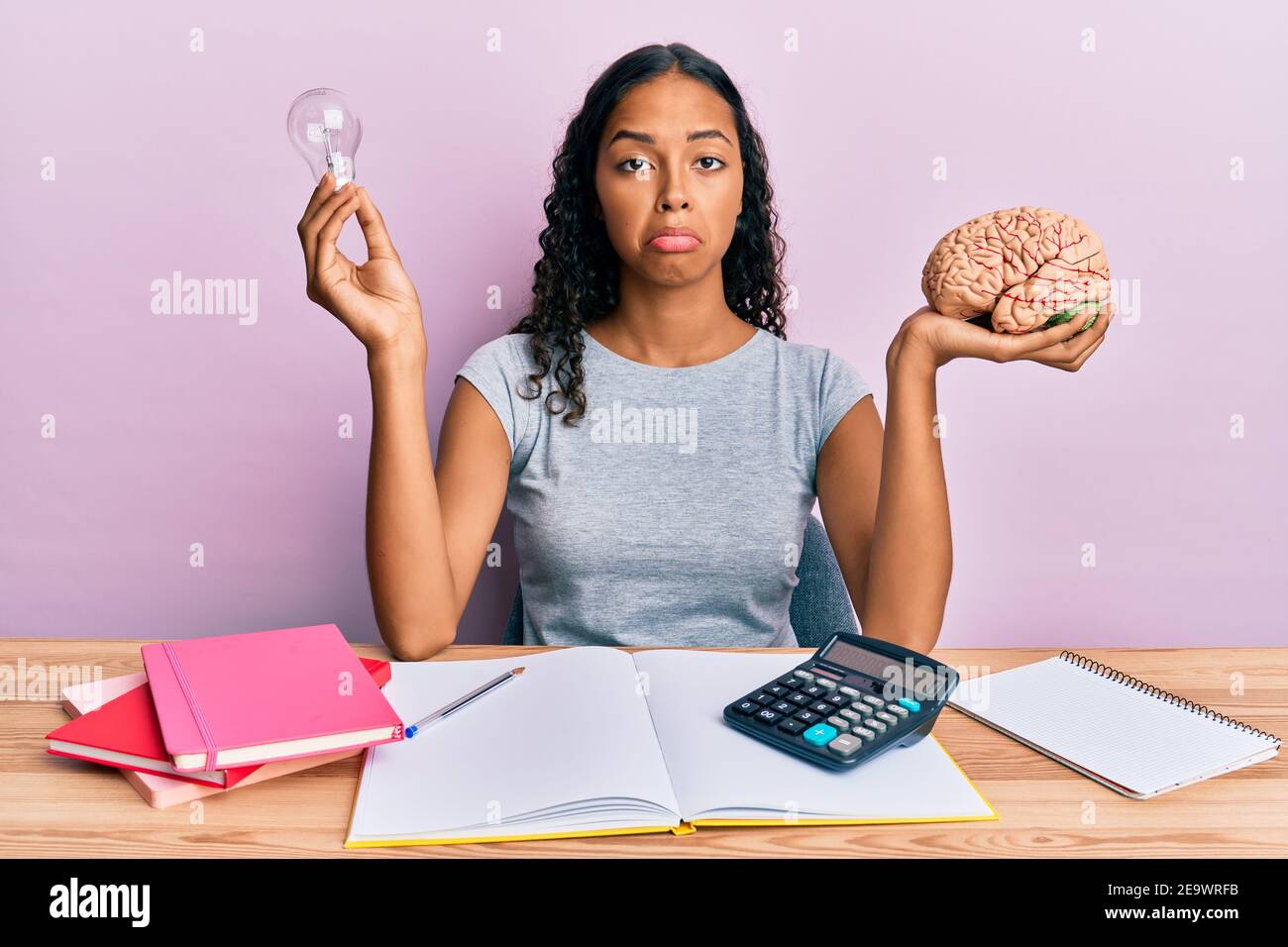 Young african american girl holding brain and light bulb studying for ...