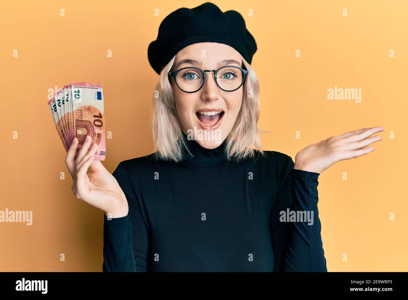 Young blonde girl holding euro banknotes celebrating achievement with ...