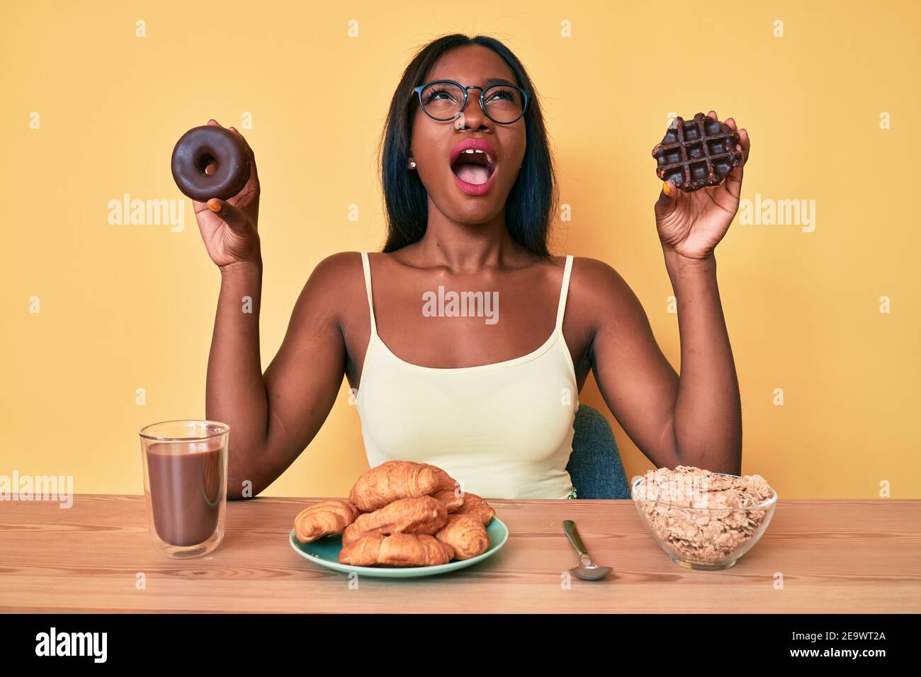 Young african american woman holding chocolate donut and waffle for ...