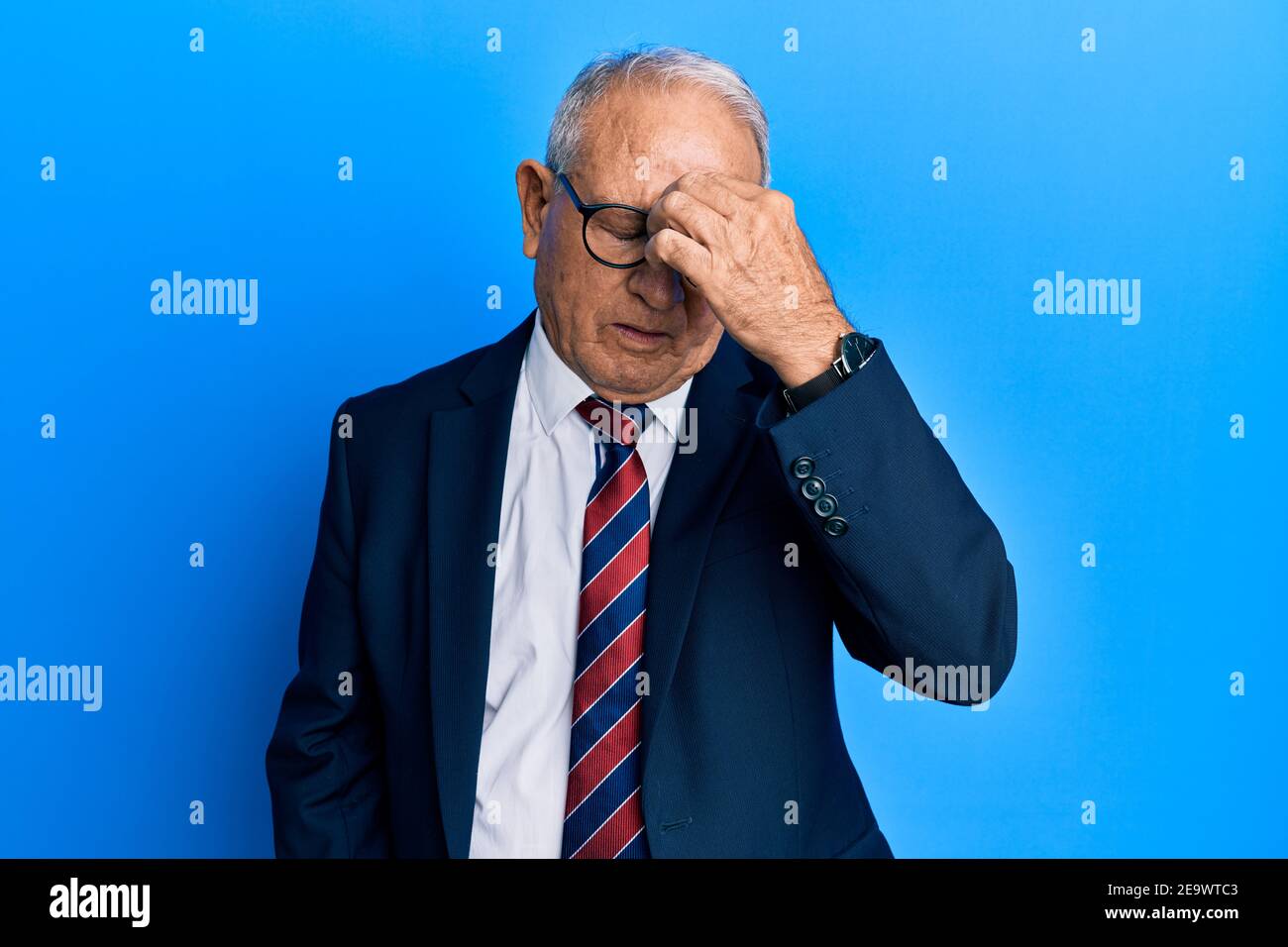 Senior caucasian man wearing business suit and tie tired rubbing nose ...