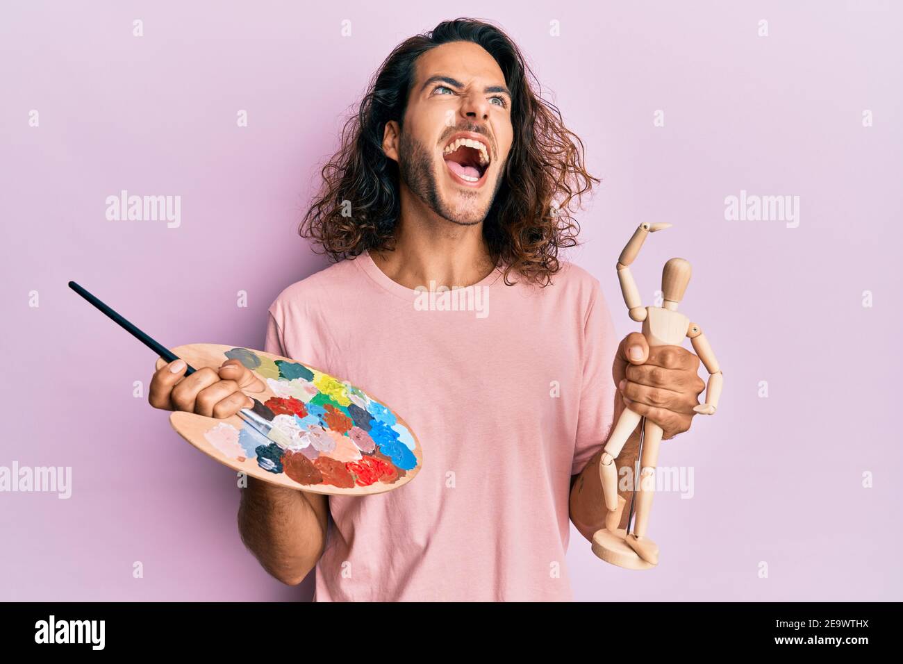 Young handsome man with long hair holding painter palette and art ...
