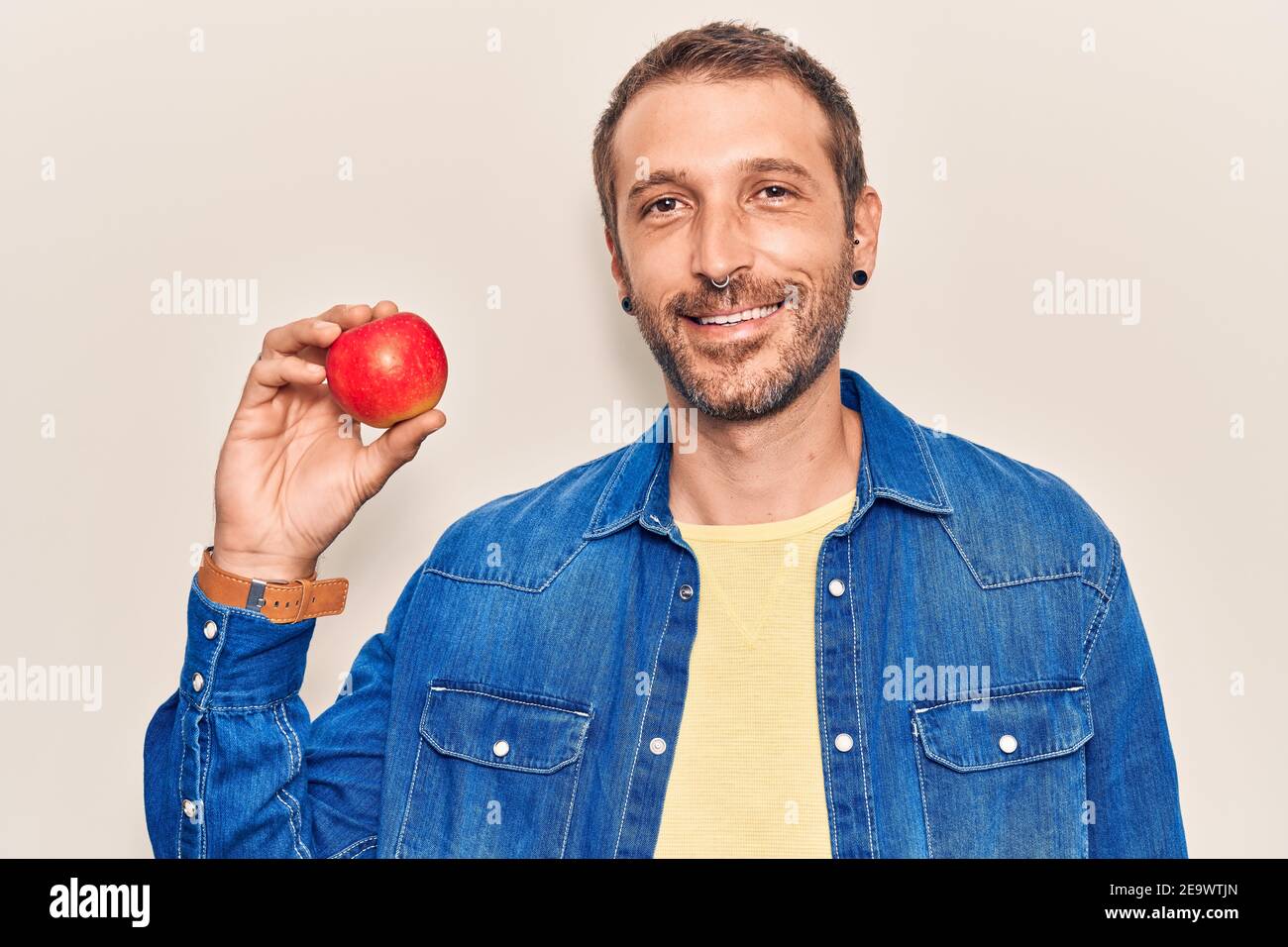Young handsome man holding red apple looking positive and happy ...