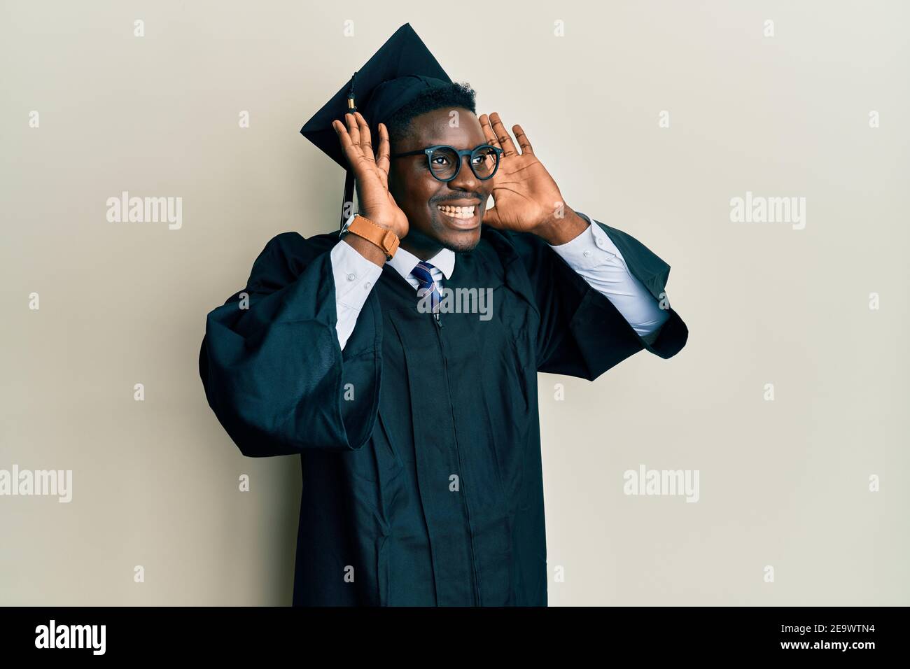 Handsome black man wearing graduation cap and ceremony robe smiling ...