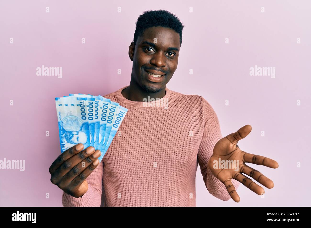 Handsome black man holding 10000 chilean pesos celebrating achievement ...